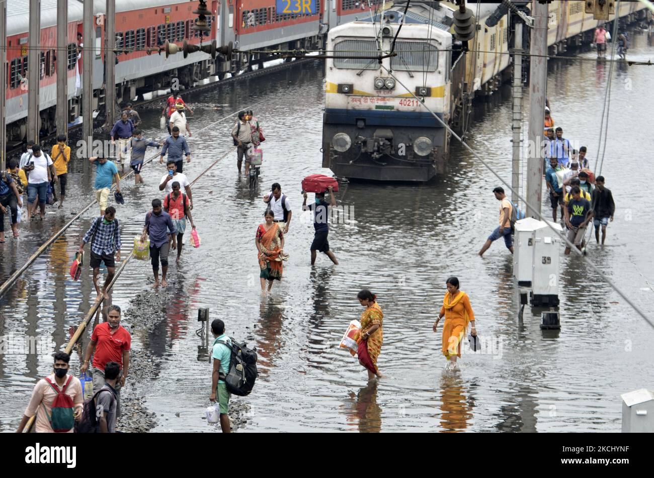 Long distance train passengers walk through the flooded railway tracks ...