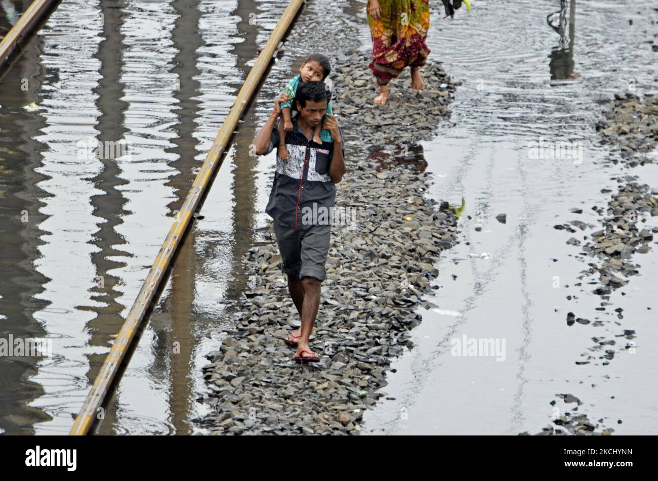 Long distance train passengers walk through the flooded railway tracks ...