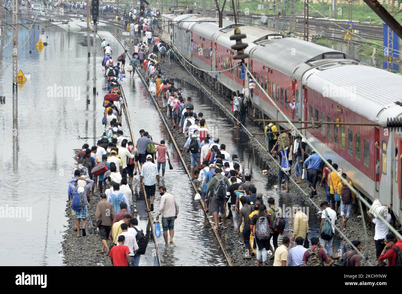 Long distance train passengers walk through the flooded railway tracks ...