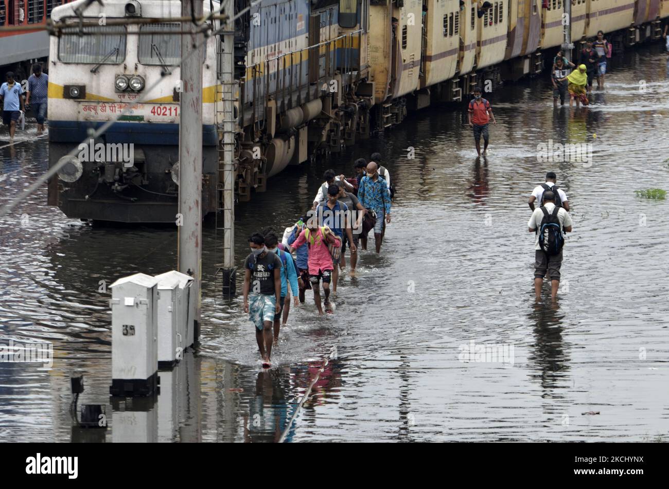 Long distance train passengers walk through the flooded railway tracks ...