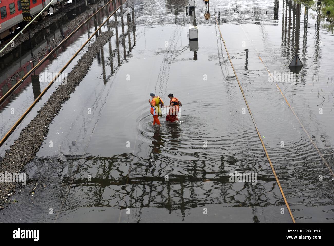 Long distance train passengers walk through the flooded railway tracks ...