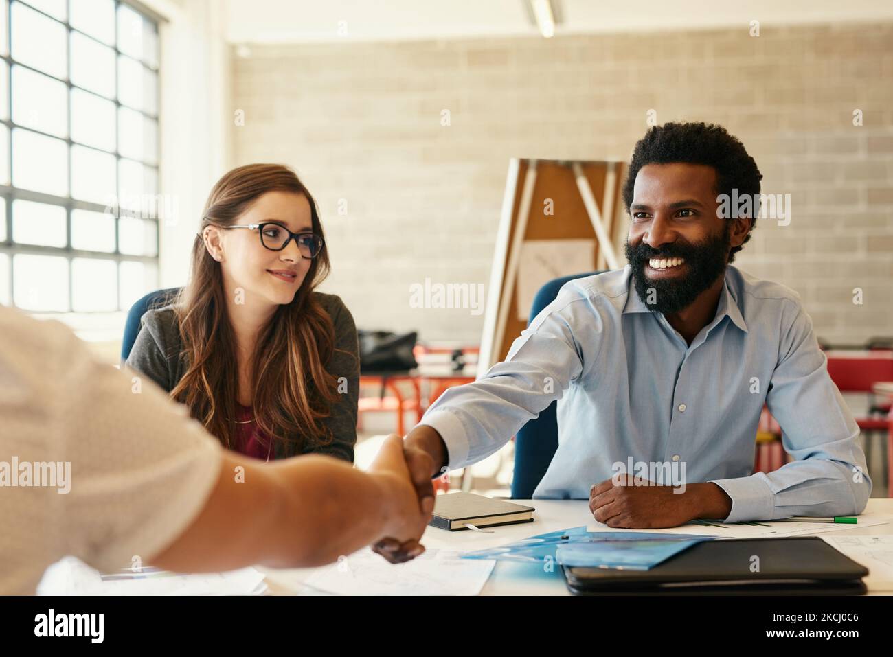 Let the merge happen. creative employees shaking hands in a modern ...