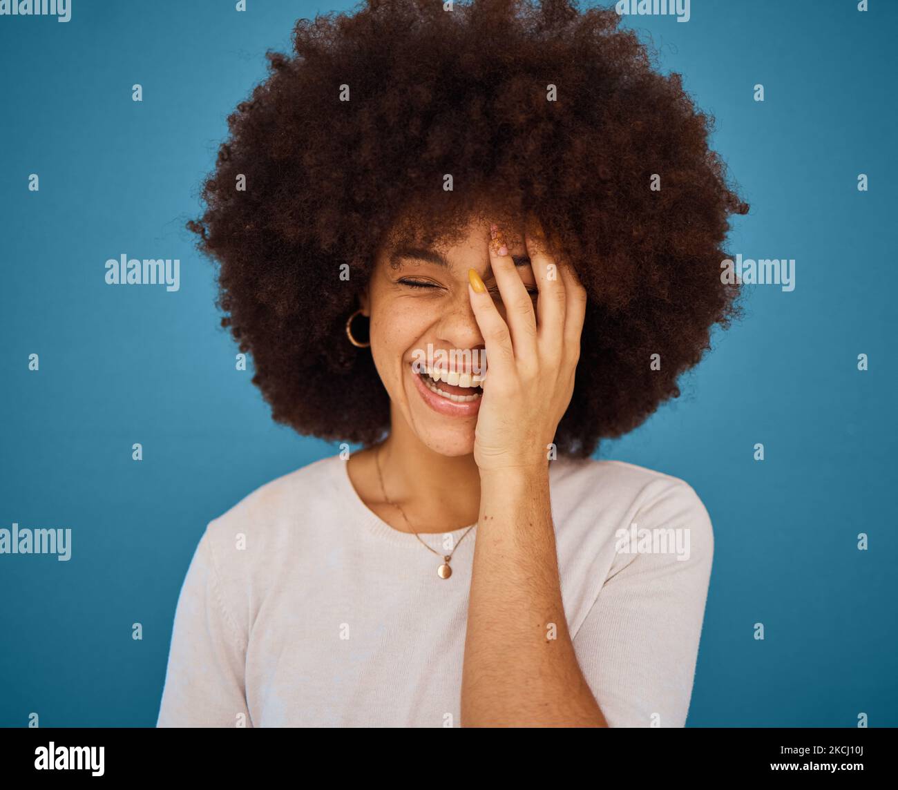Face, funny and laughing with an afro black woman in studio on a blue ...