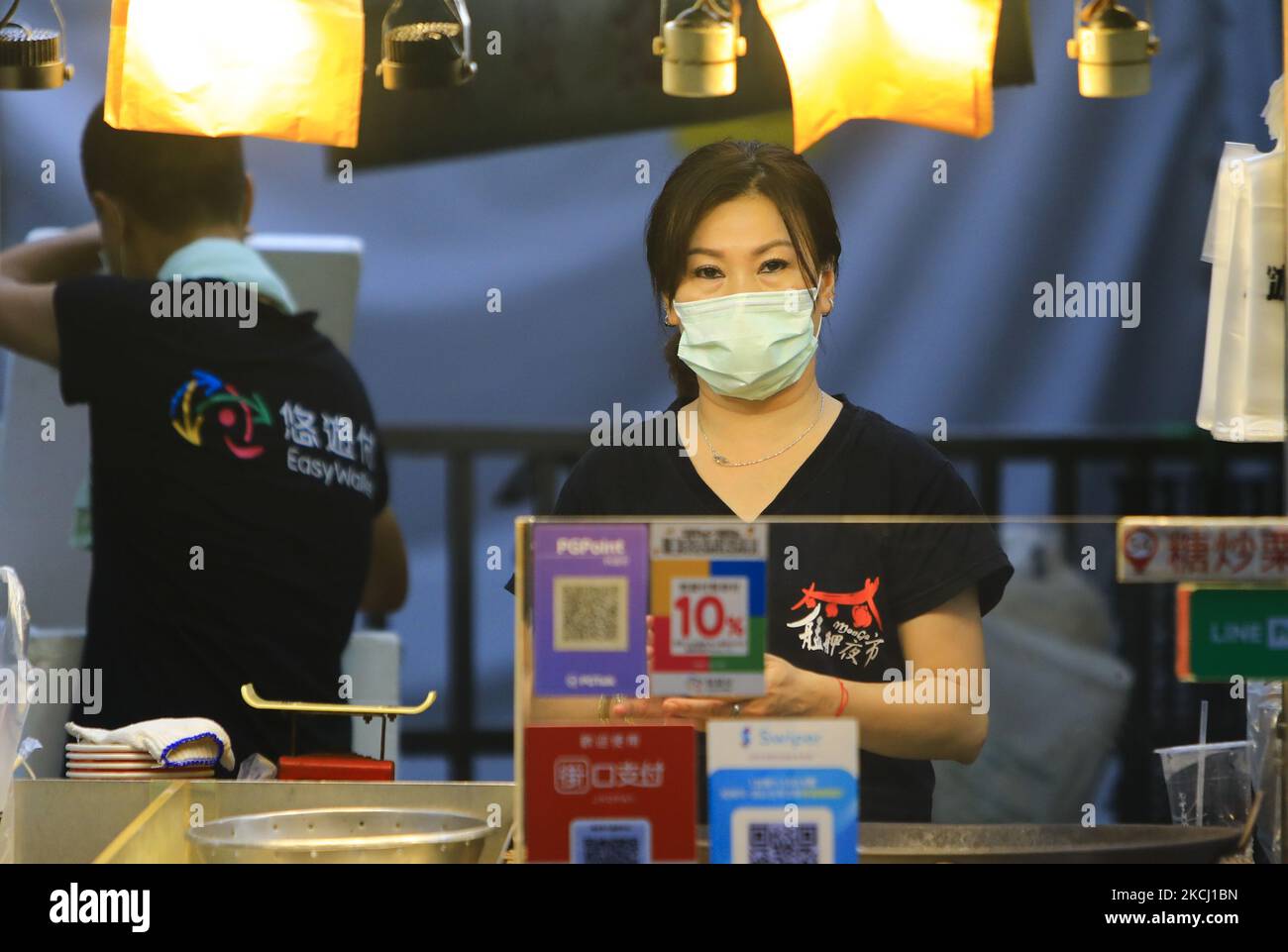 A food hawker with a face mask at a night market in Wanhua District ...
