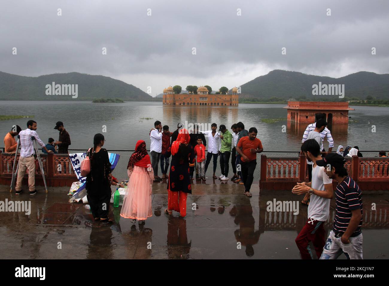 People enjoy at ' Jal Mahal' as clouds hover over it on a rainy day ...