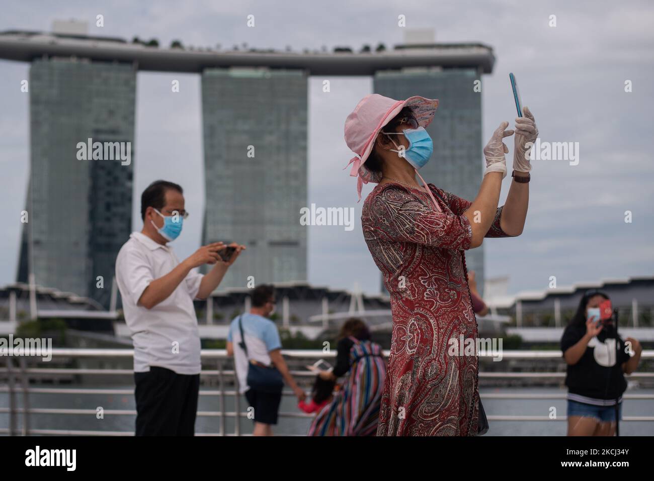 A woman wearing 2 masks and gloves takes pictures at Singapore's Marina ...