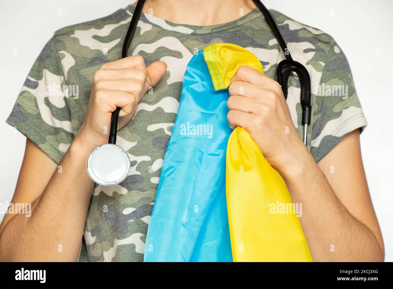 Military nurse with a stethoscope and the flag of Ukraine in her hands ...