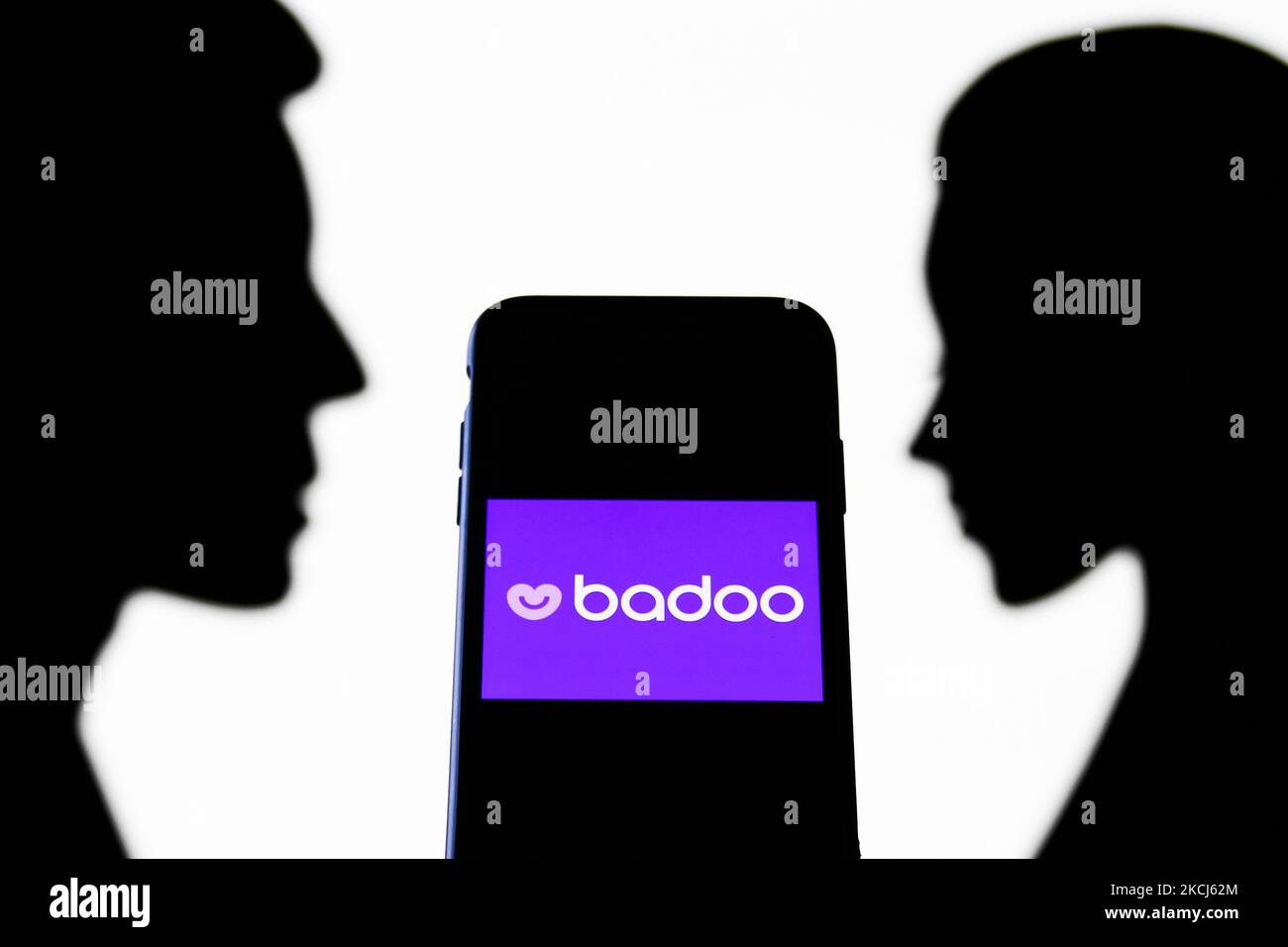 Badoo logo displayed on a phone screen is seen with paper silhouettes ...