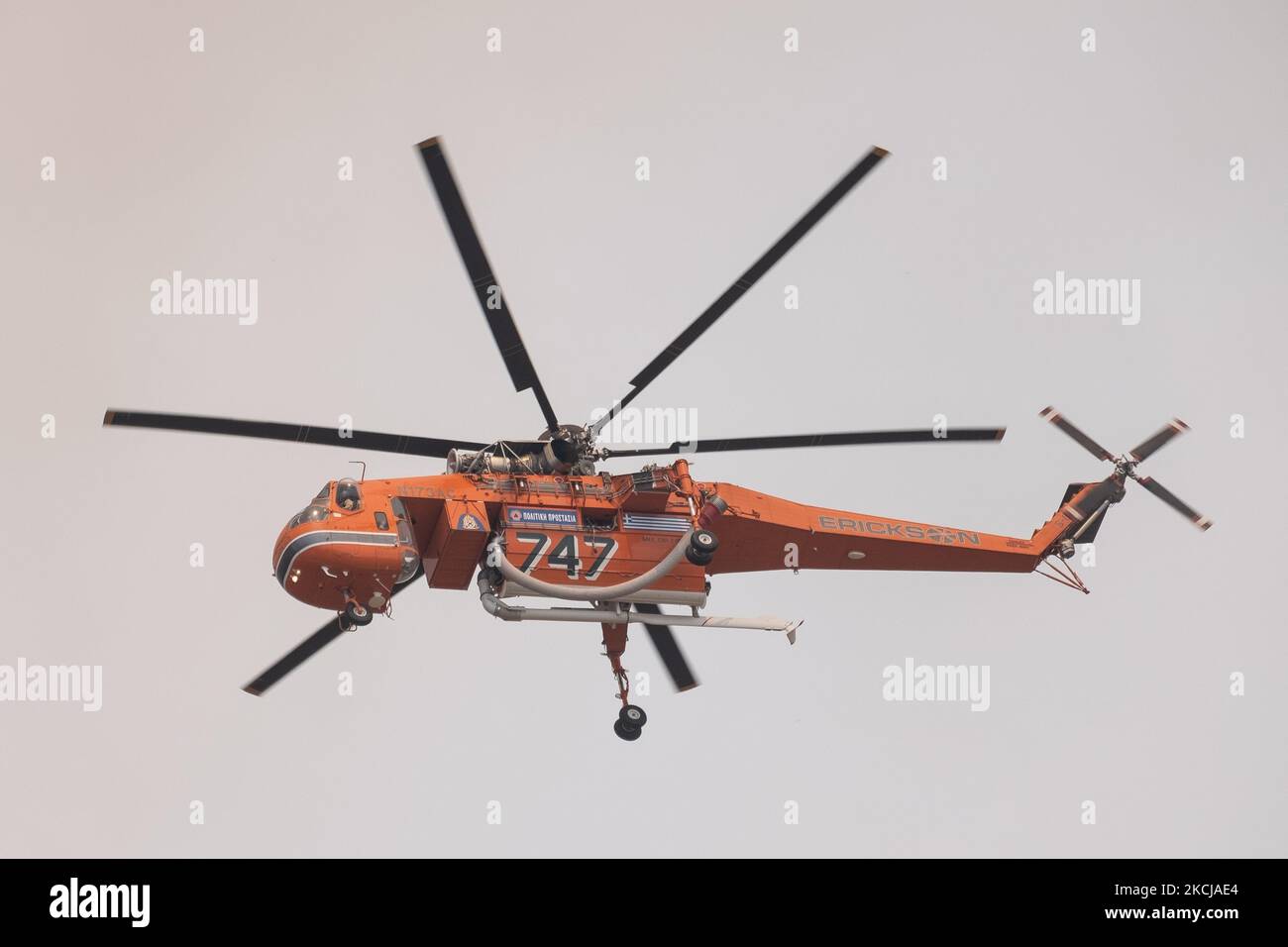 An Erickson fire fighting helicopter is flying above the fire. A ...