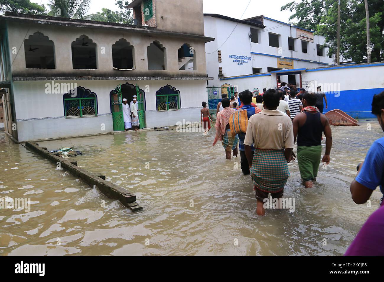 People wade through a waterlogged street in the flood hit city of Amta ...