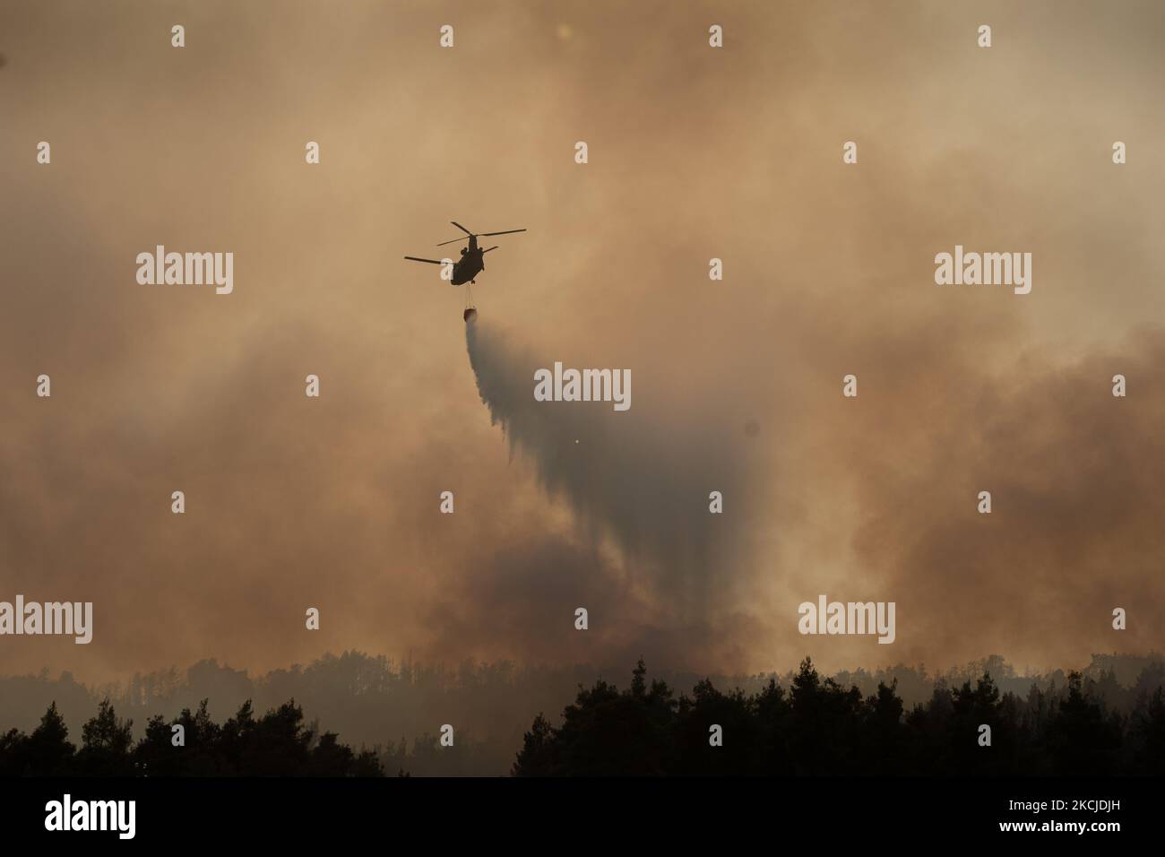 A firefighting helicopter releasing buckets of water during the ...