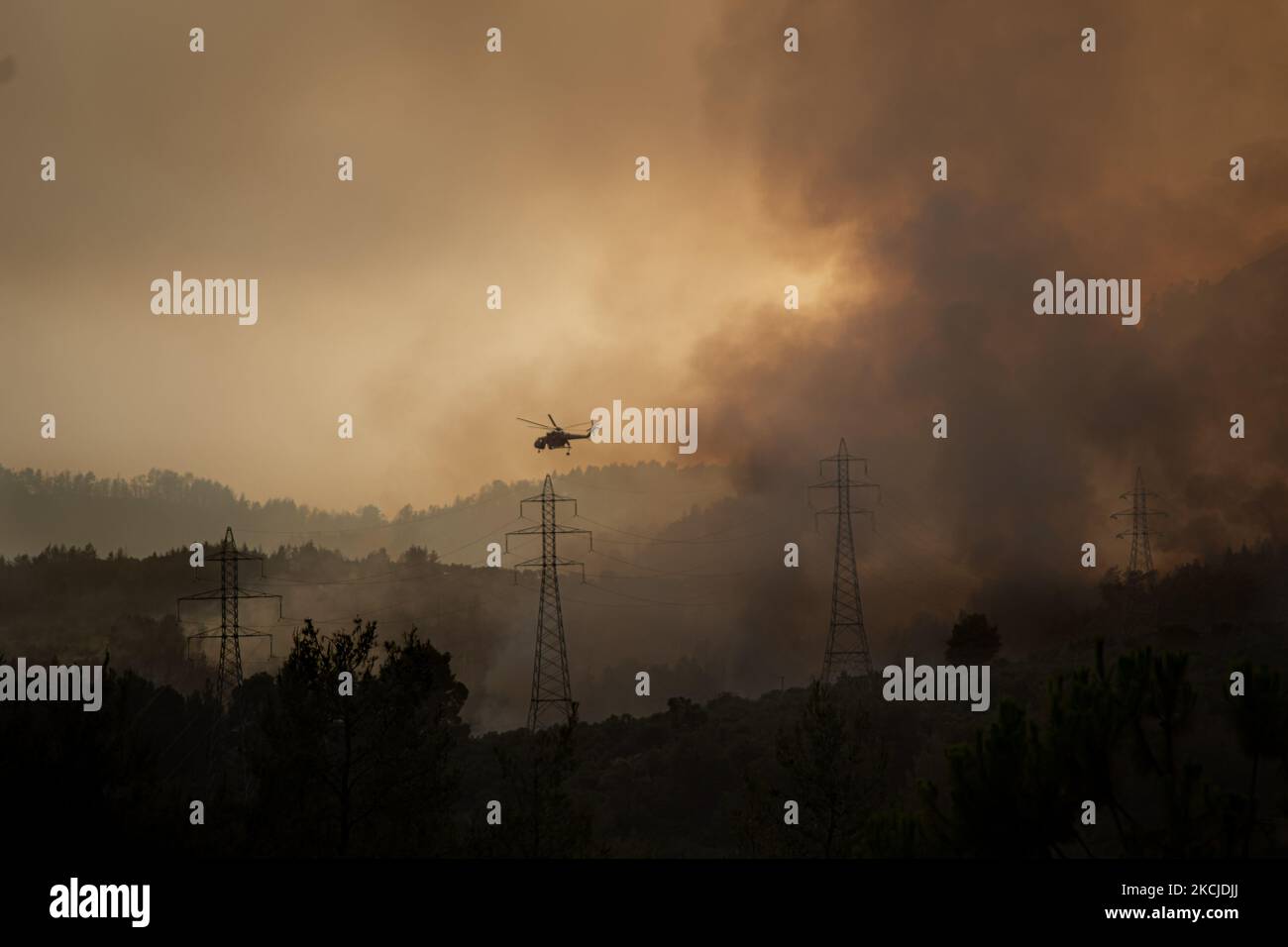A firefighting helicopter releasing buckets of water during the ...