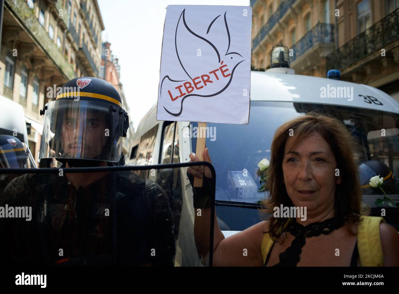 A woman poses near a riot policmena in full gear with a drawing of dove ...