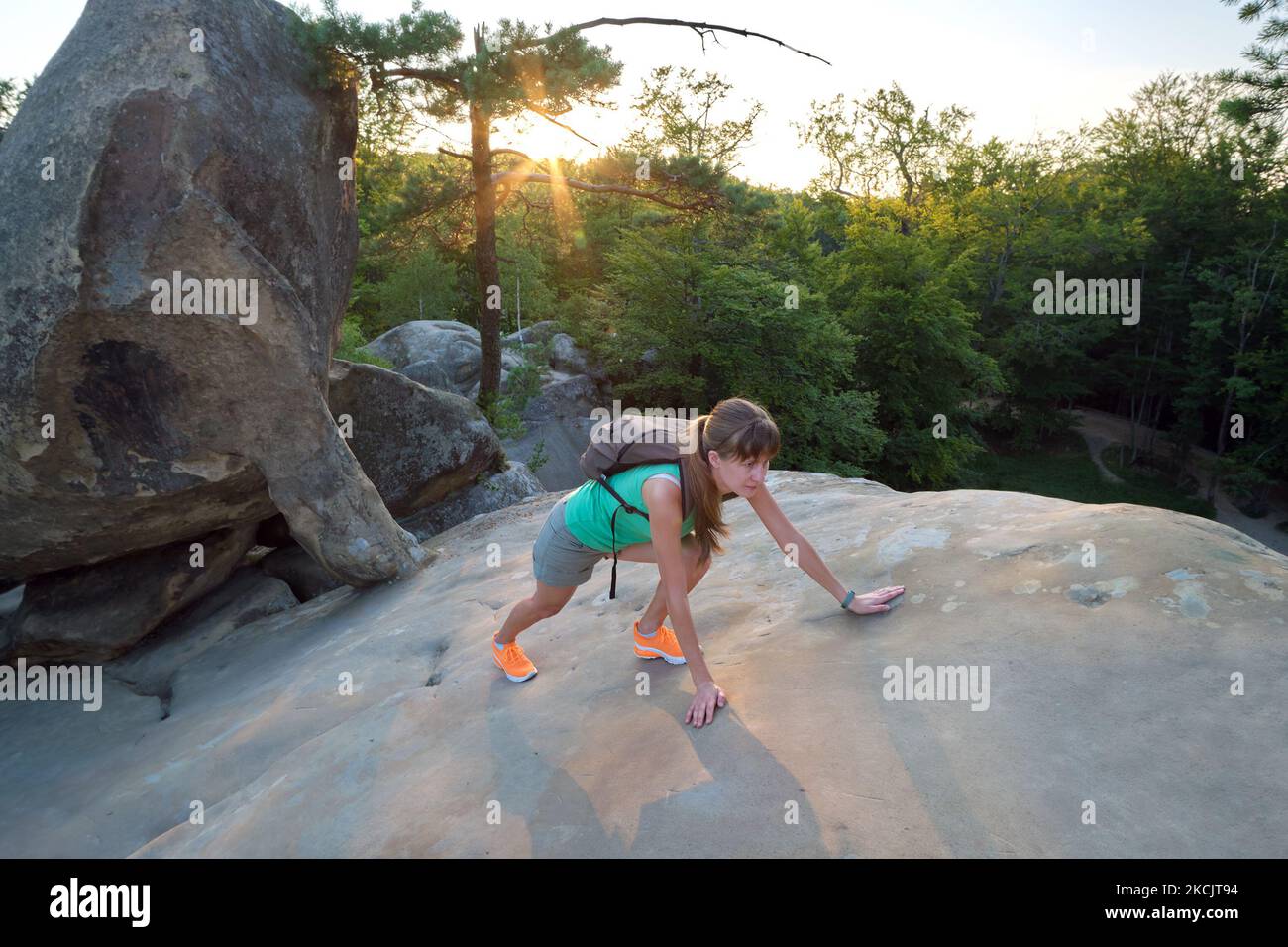 Sportive woman climbing alone on hillside rocky trail. Female hiker ...