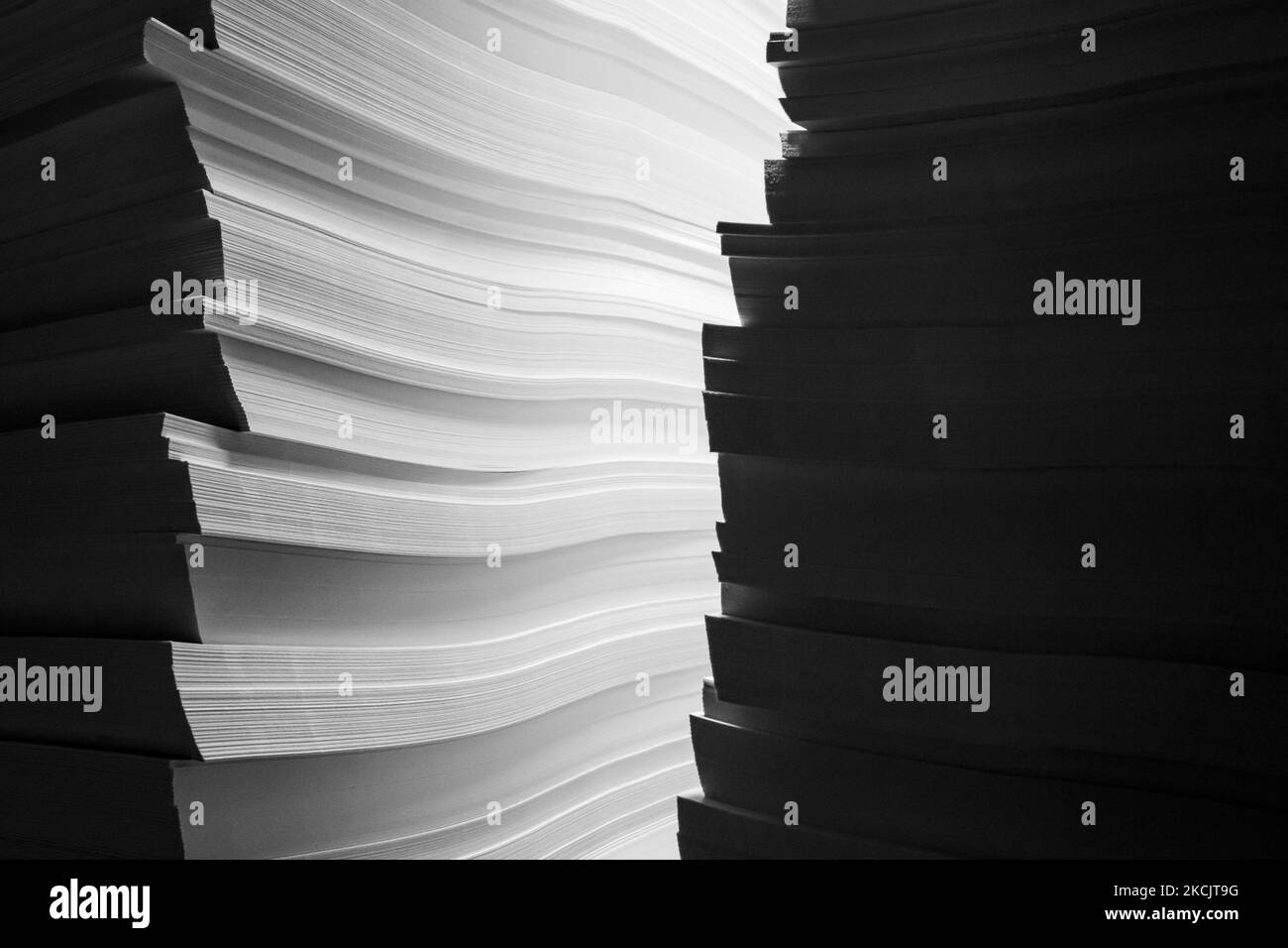 Piles of blank paper for printing illuminated with bright light in dark ...