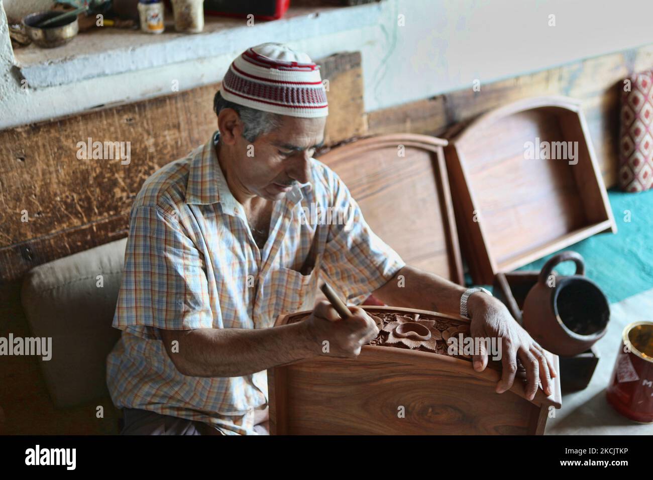 Kashmiri craftsman polishes a hand carved walnut drawer in a small ...