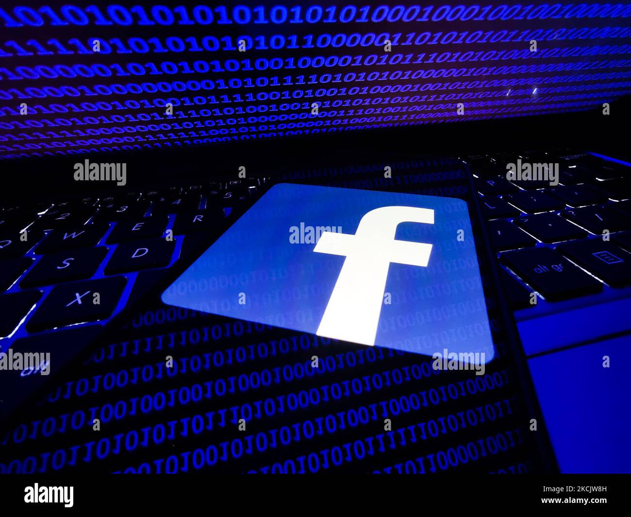 Facebook logo displayed on a phone screen is seen with binary code ... Facebook logo displayed on a phone screen is seen with binary code ...