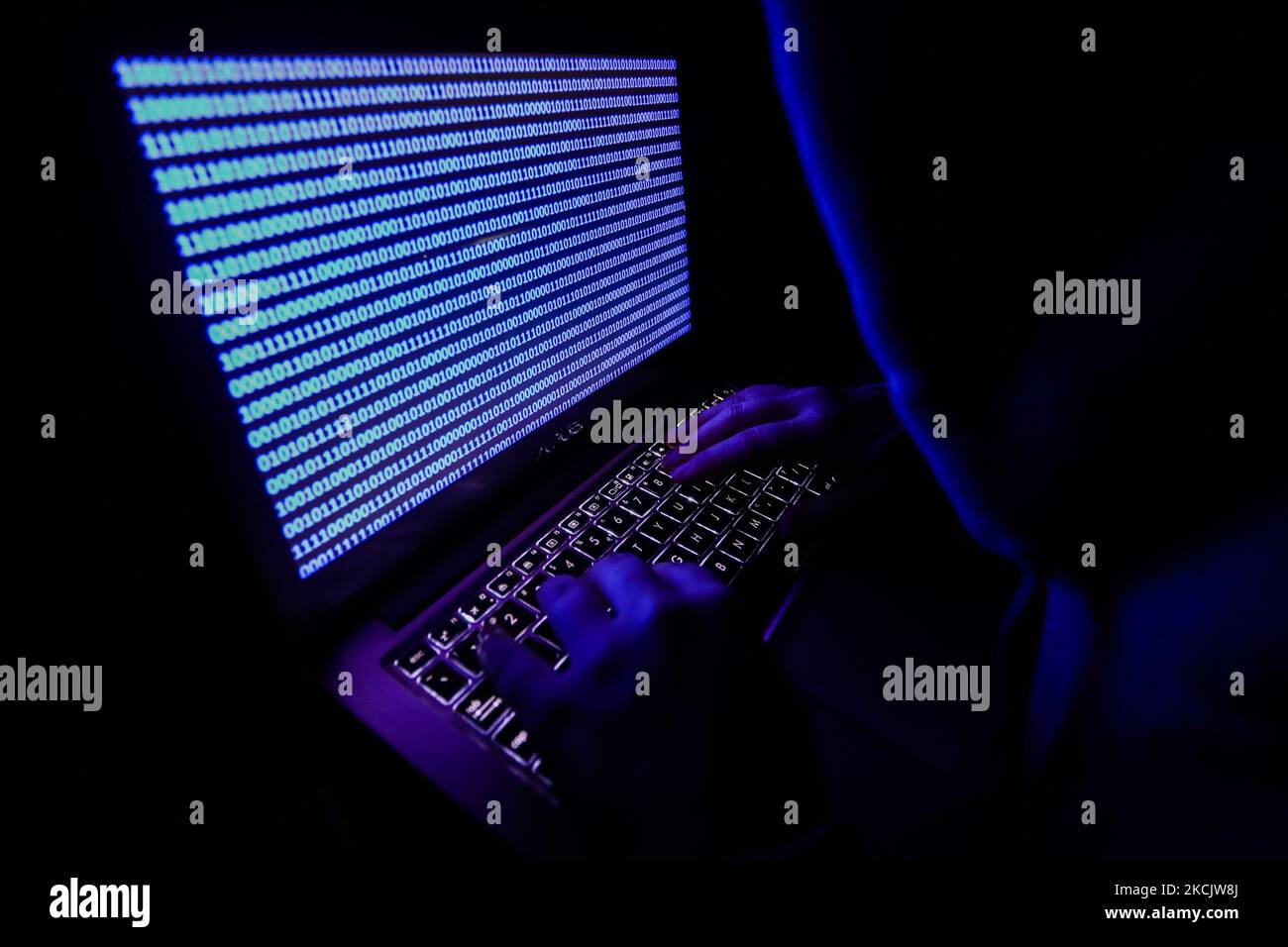A person dressed as an internet hacker is seen with binary code ...