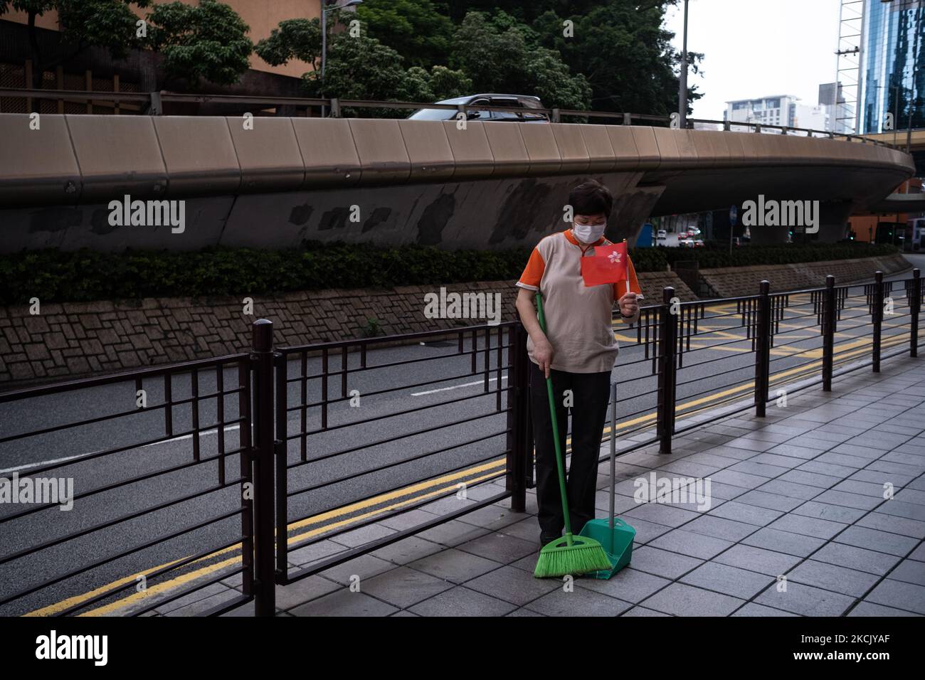 A cleaning worker is holding the Chinese flag and the Hong Kong ...