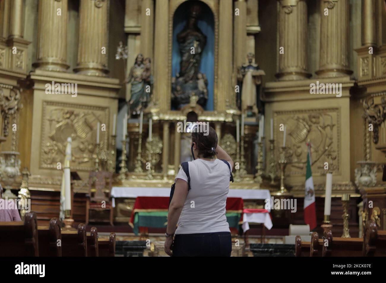 A woman takes a photograph with her mobile phone inside a church in the ...