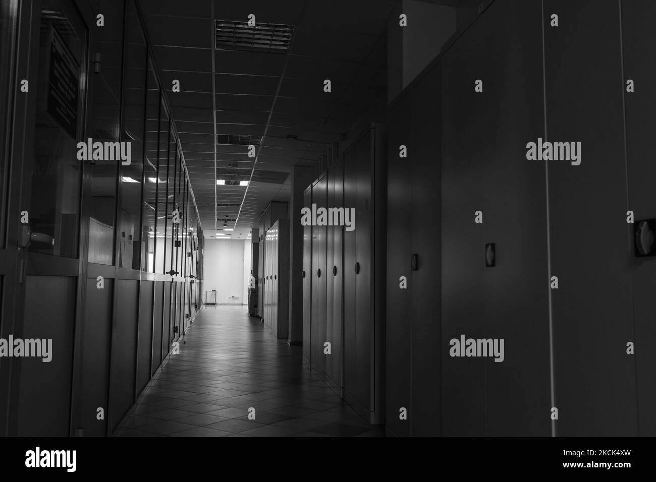 Narrow dark corridor with dim light in end inside modern building at ...