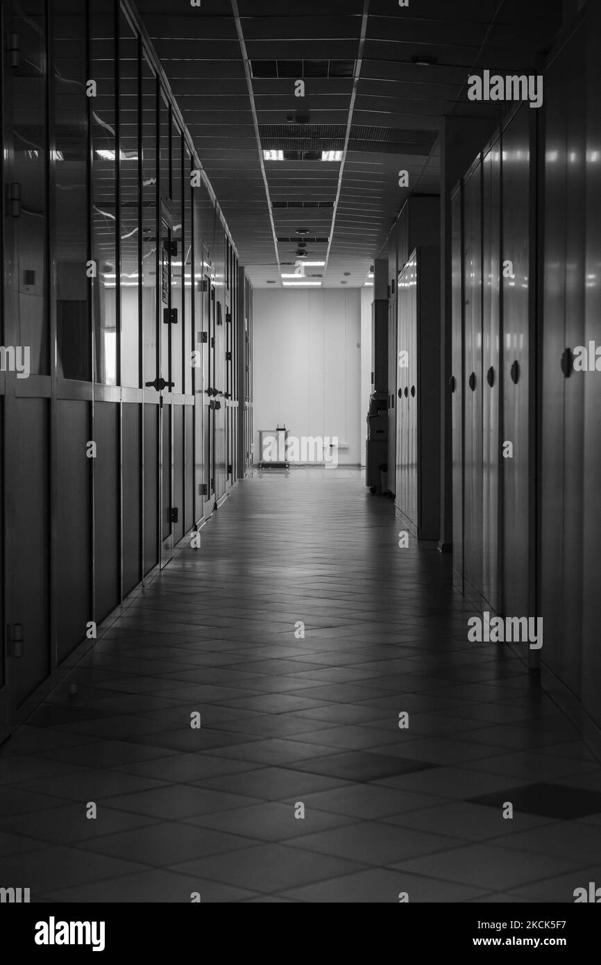 Narrow dark corridor with dim light in end inside modern building at ...