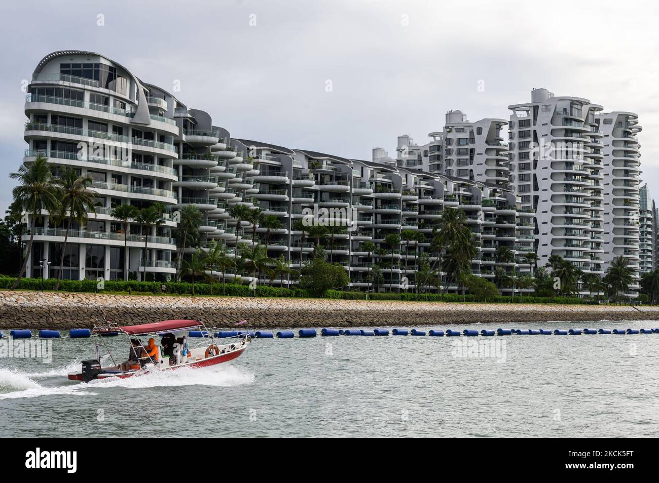 A small fishing boat passes by luxury waterfront condomiums in the ...