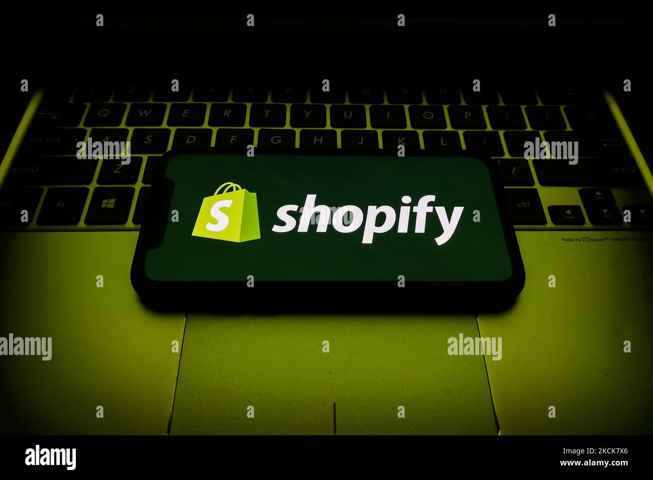 Shopify logo displayed on a phone screen and a laptop keyboard are seen ...