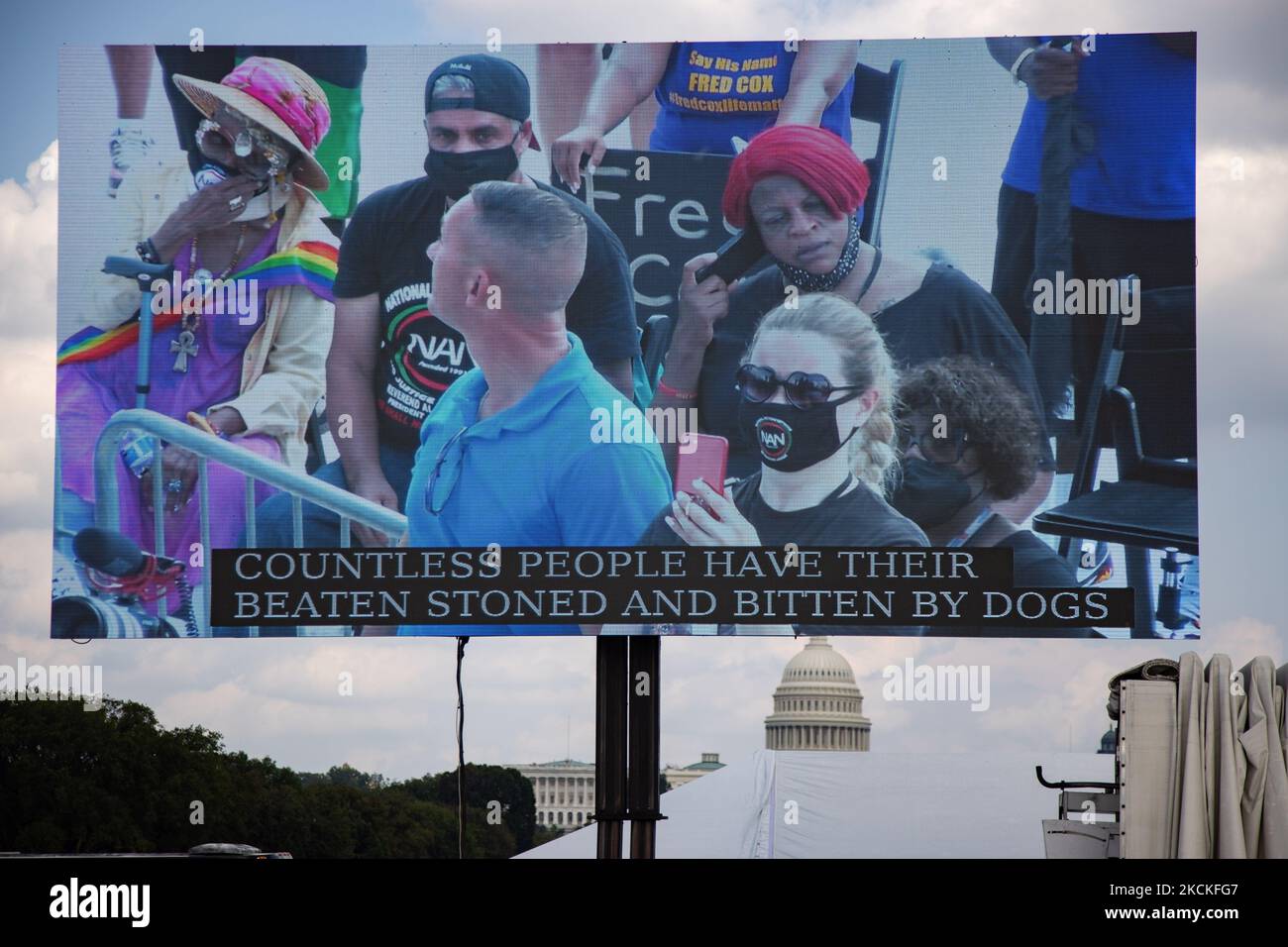 People, seen on a large television screen, attend the "March On for ...