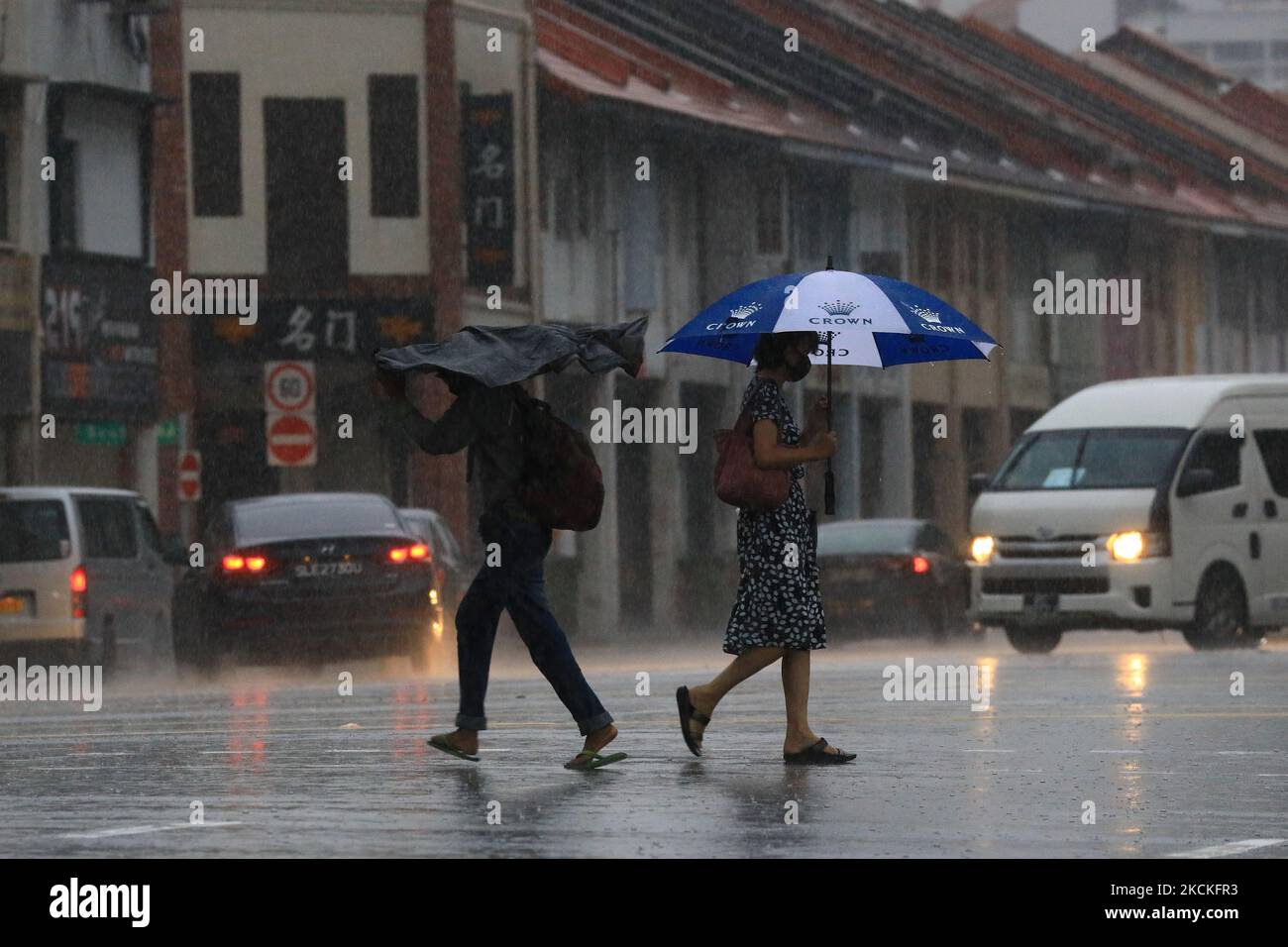 People cross a road in the rain on August 30, 2021 in Singapore. (Photo ...