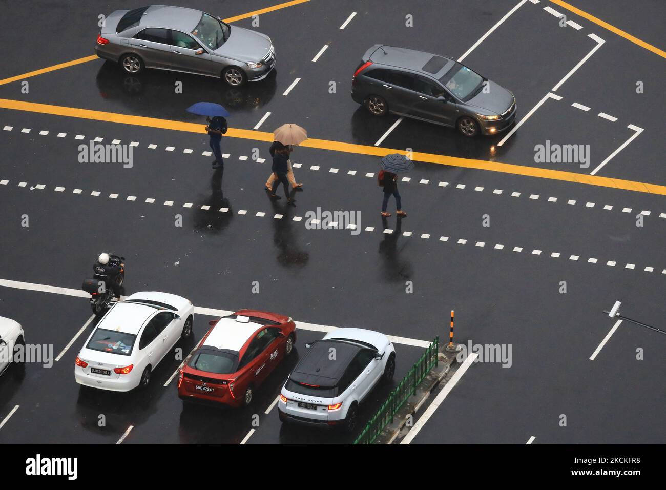 People cross a road in the rain on August 30, 2021 in Singapore. (Photo ...