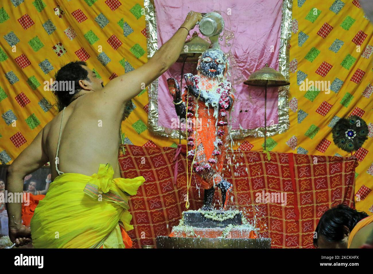 A priest performs 'Abhishek' to Lord Krishna on the occasion of ...