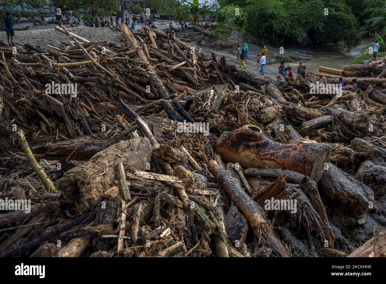Residents are near piles of pieces of wood that were carried away by ...