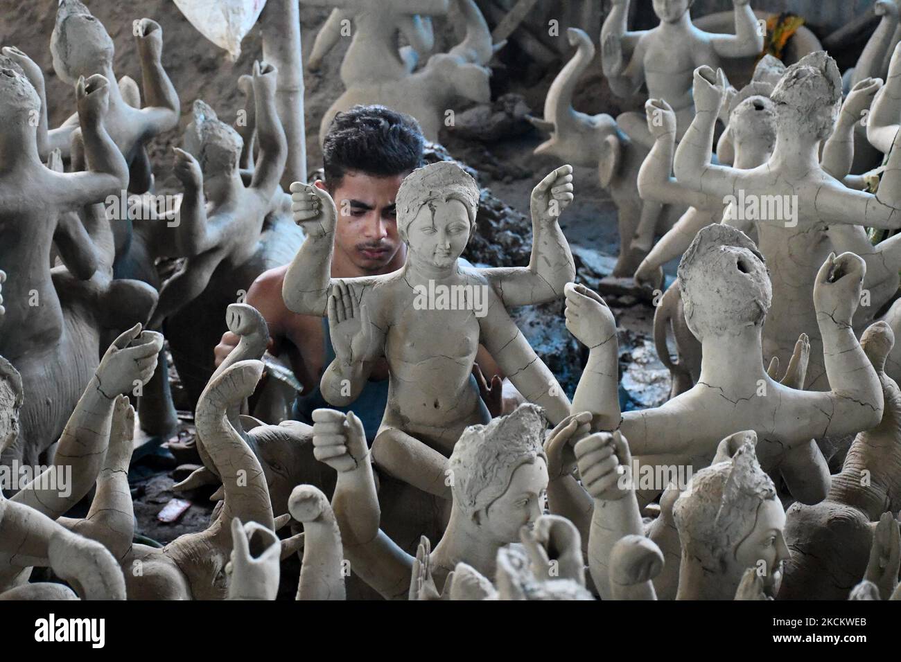 An Indian idol maker adds a mud layer on a semi-finished clay idol of ...