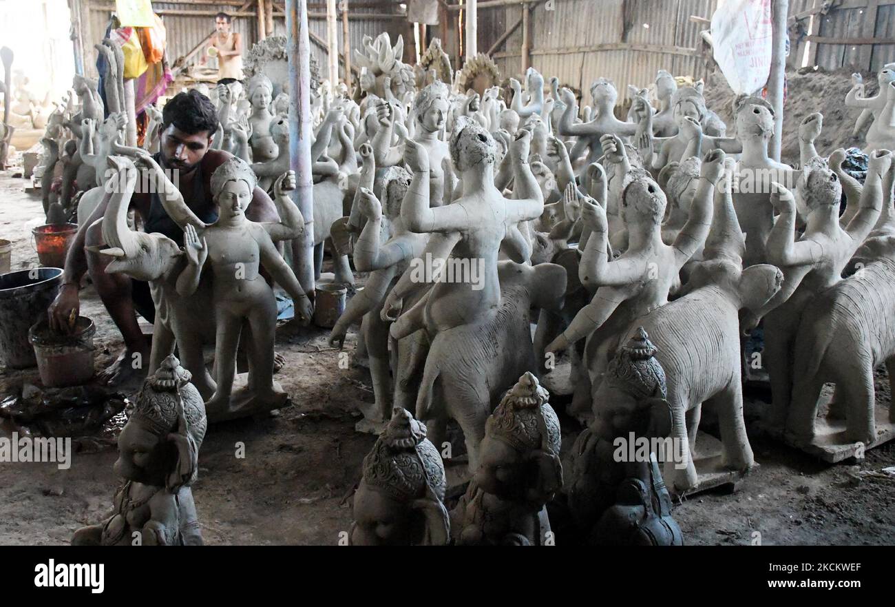 An Indian idol maker adds a mud layer on a semi-finished clay idol of ...