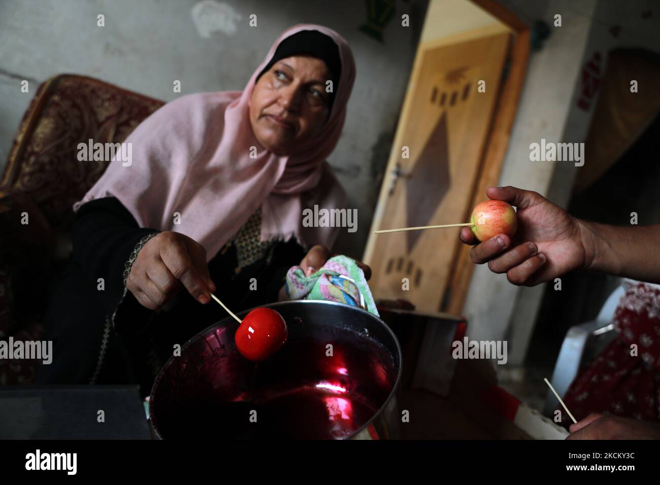 Palestinian Hanan Hamad, 50, makes candy apples with colored honey ...