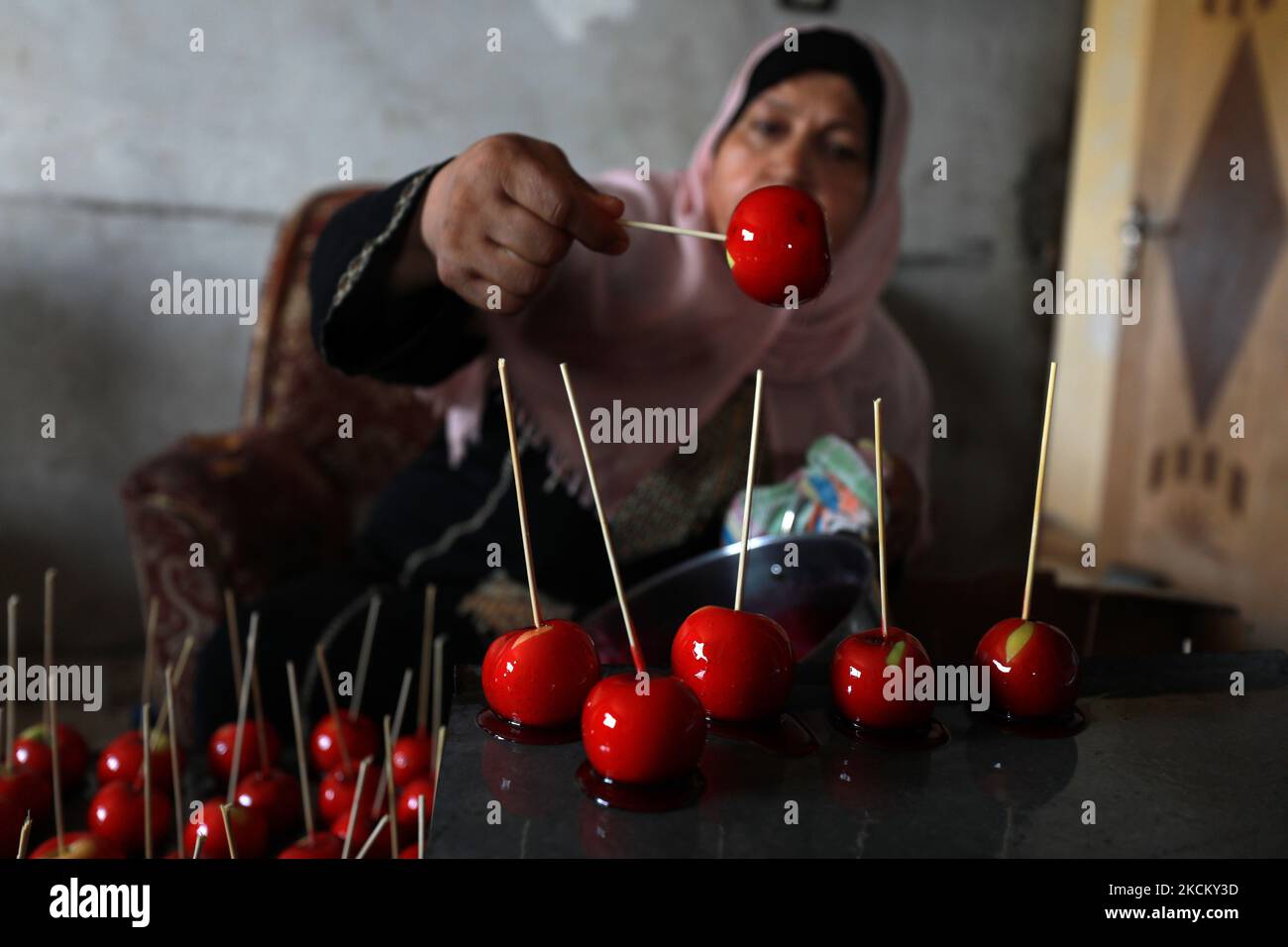 Palestinian Hanan Hamad, 50, makes candy apples with colored honey ...