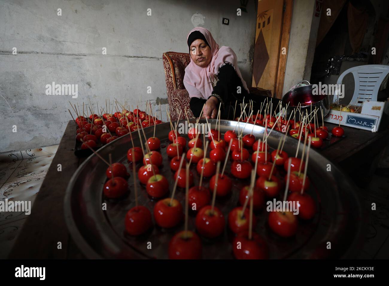 Palestinian Hanan Hamad, 50, makes candy apples with colored honey ...