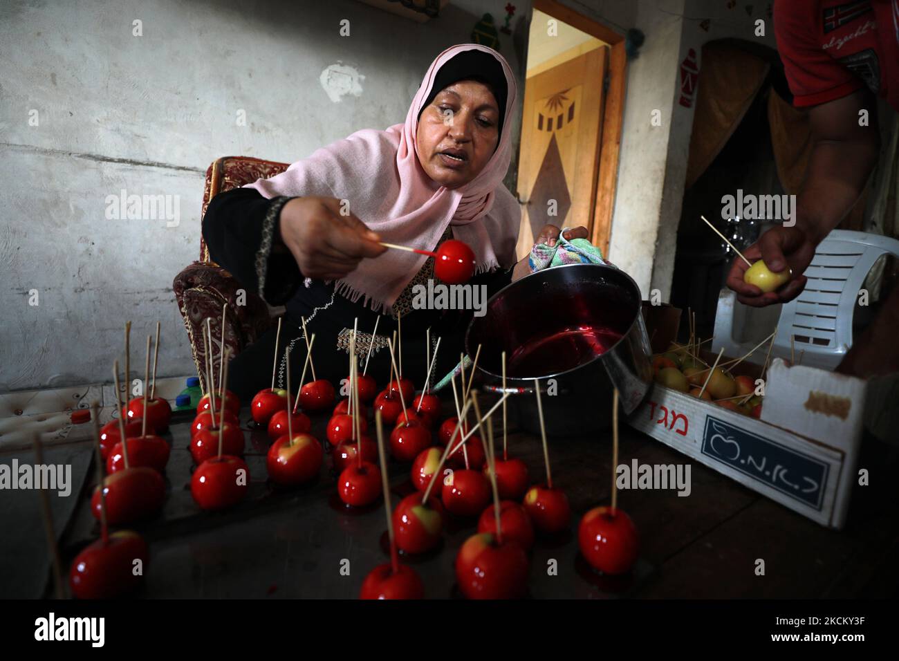 Palestinian Hanan Hamad, 50, makes candy apples with colored honey ...