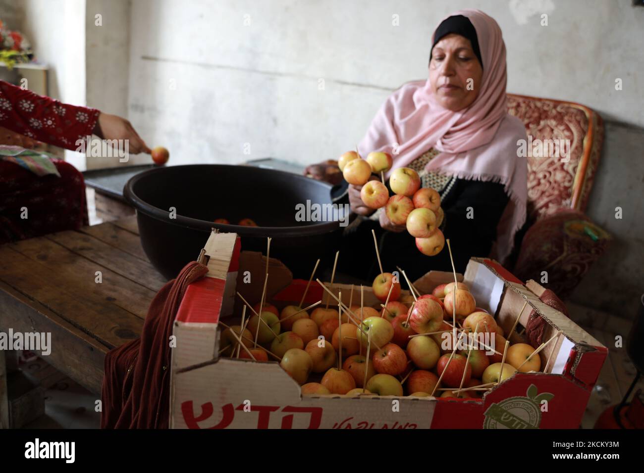 Palestinian Hanan Hamad, 50, makes candy apples with colored honey ...