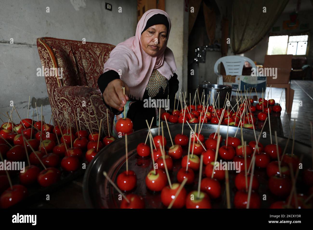 Palestinian Hanan Hamad, 50, makes candy apples with colored honey ...