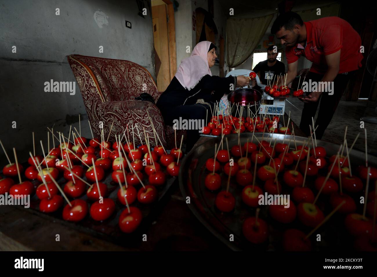 Palestinian Hanan Hamad, 50, makes candy apples with colored honey ...