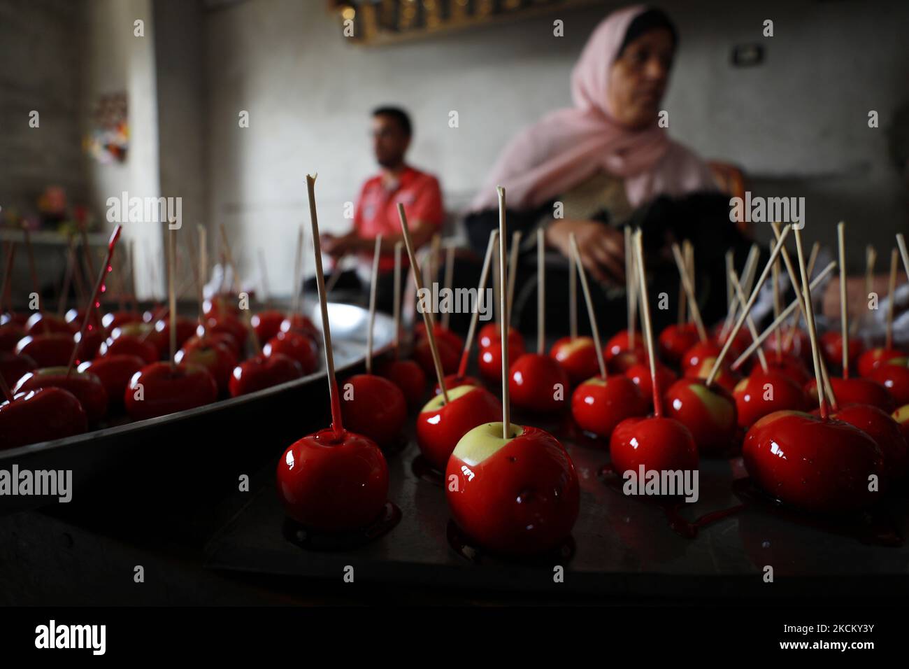 Palestinian Hanan Hamad, 50, makes candy apples with colored honey ...