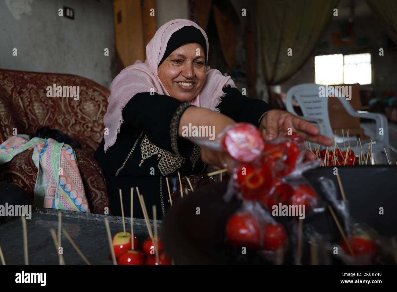 Palestinian Hanan Hamad, 50, makes candy apples with colored honey ...