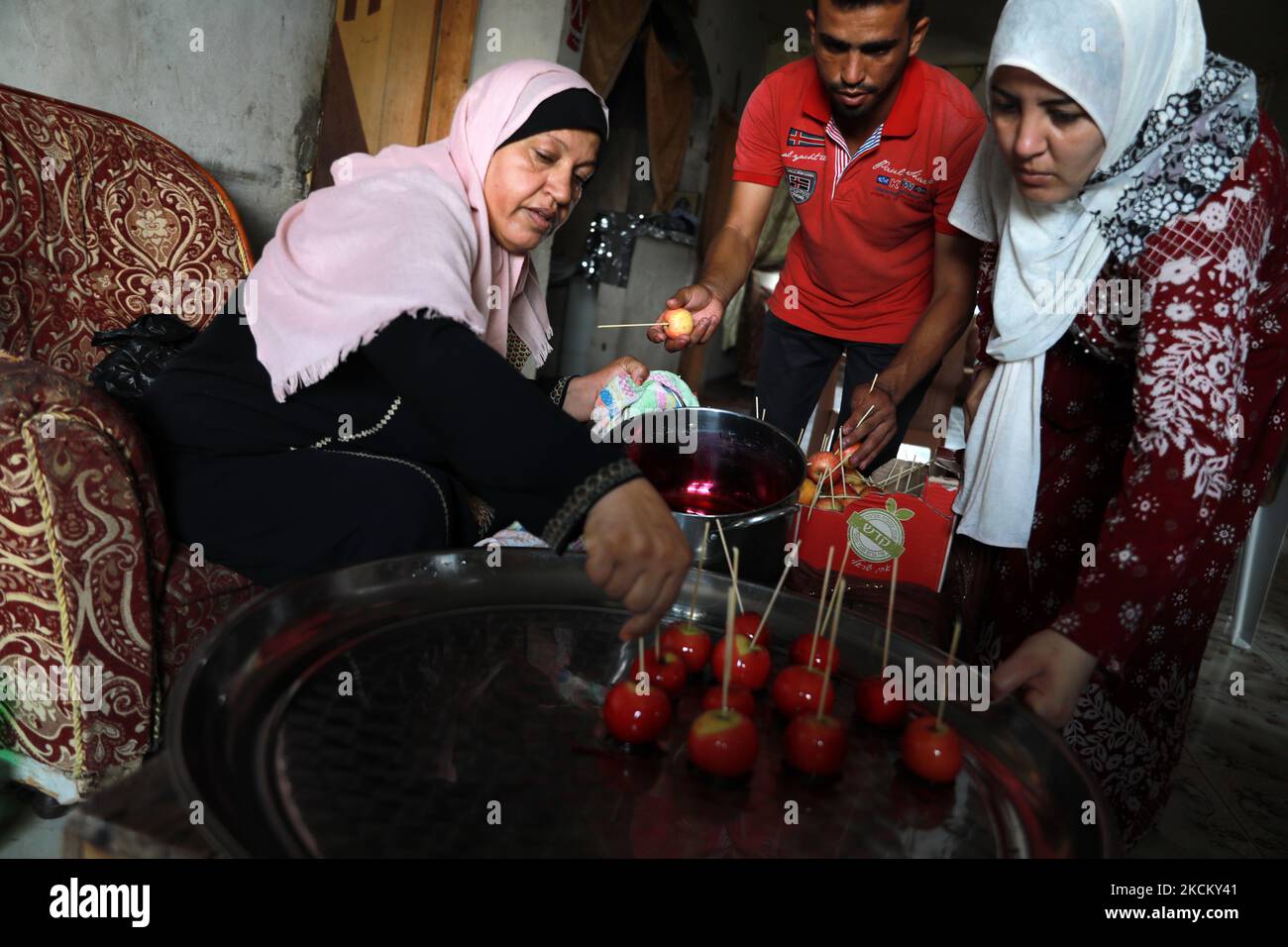 Palestinian Hanan Hamad, 50, makes candy apples with colored honey ...