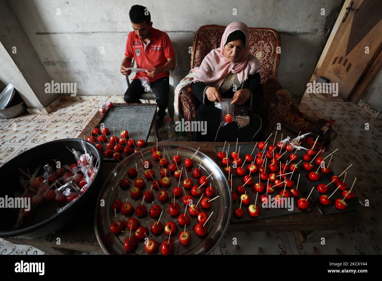 Palestinian Hanan Hamad, 50, makes candy apples with colored honey ...