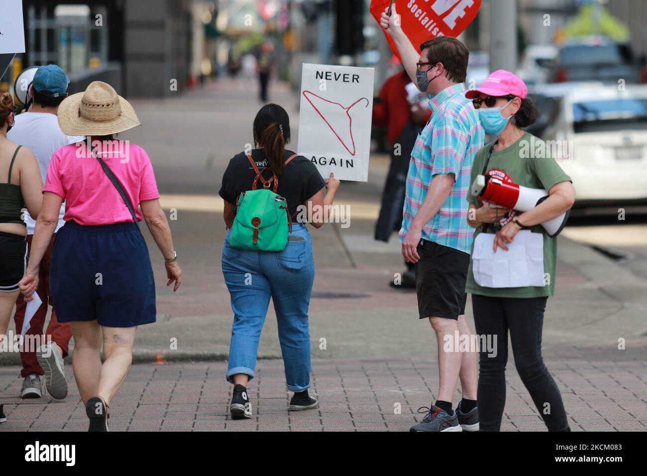 The back of a protestor's sign displays only a coat hanger as she ...