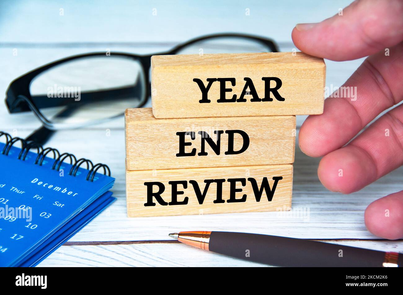 Year end review text on wooden blocks with December calendar, glasses and pen. Year end review ...