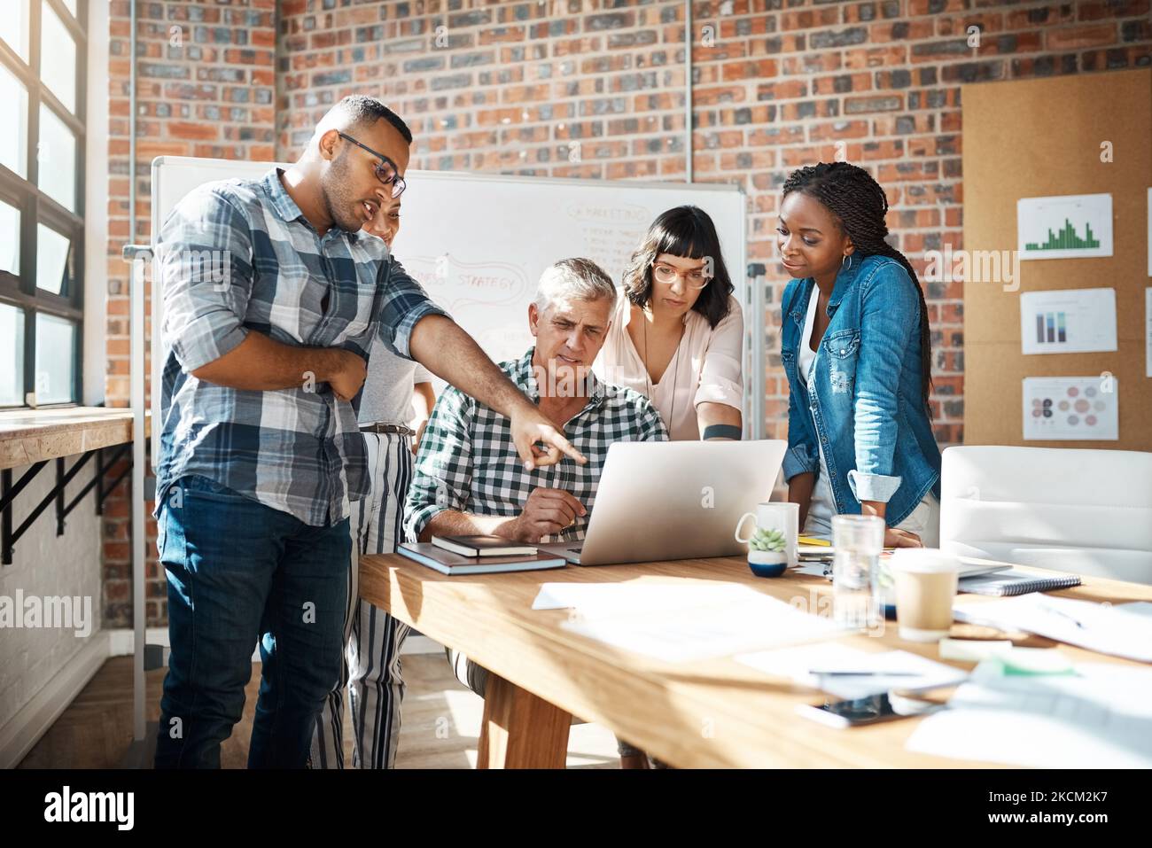 Teamwork simplifies the task. a group of colleagues using a laptop ...