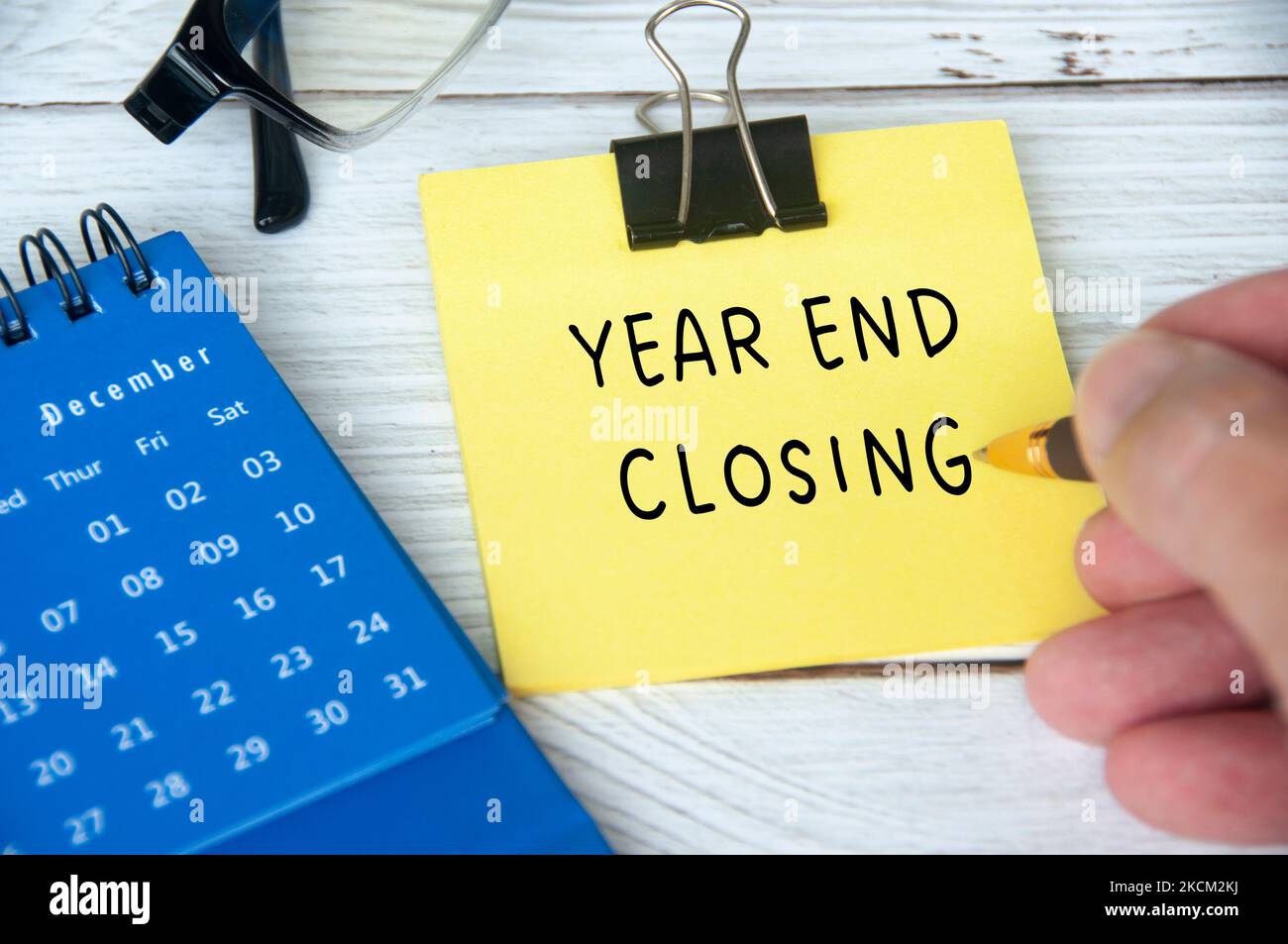 Year end closing written on yellow notepad with December calendar and ...